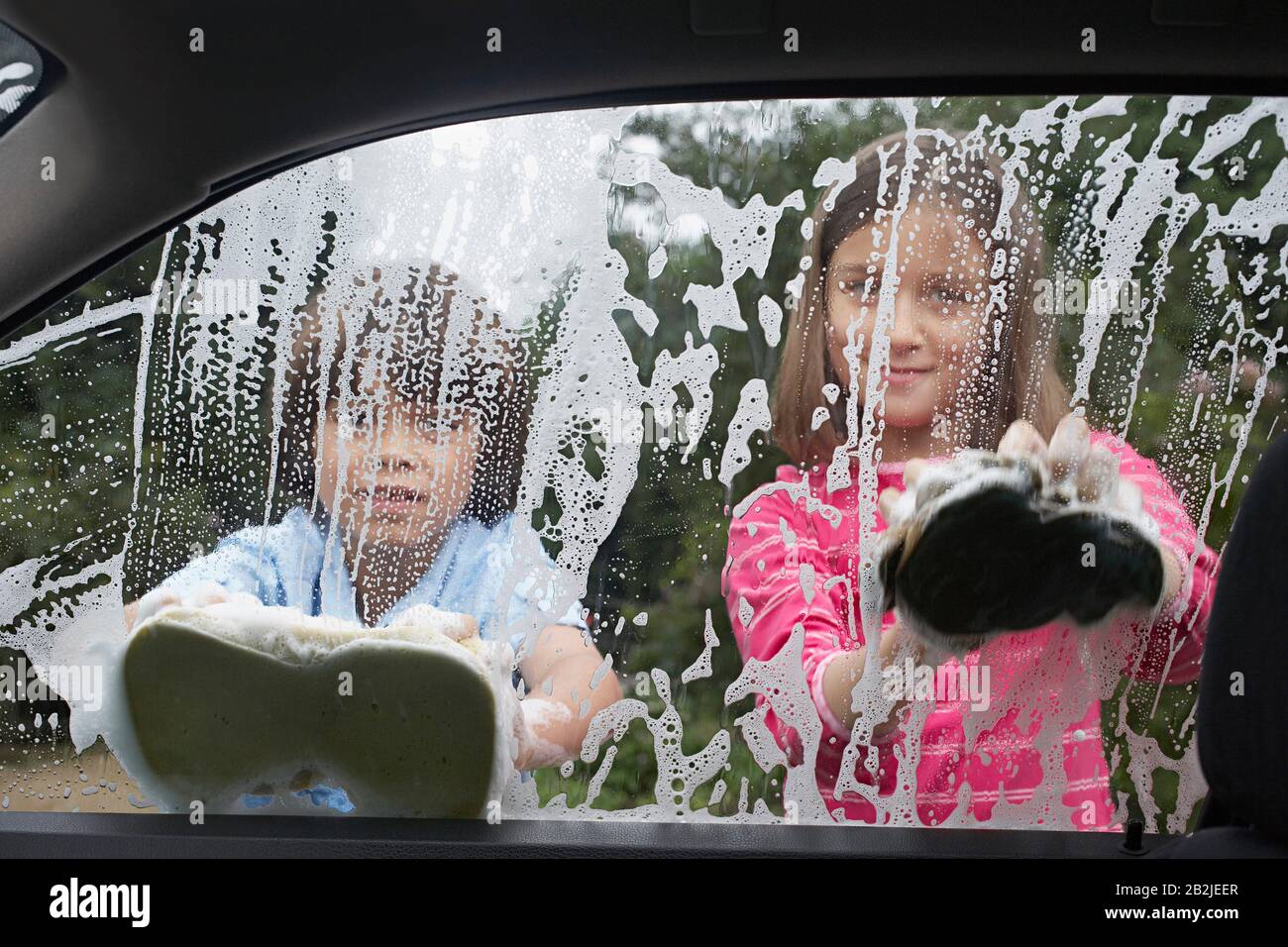 Boy and girl (7-9) washing car together view from inside car Stock ...