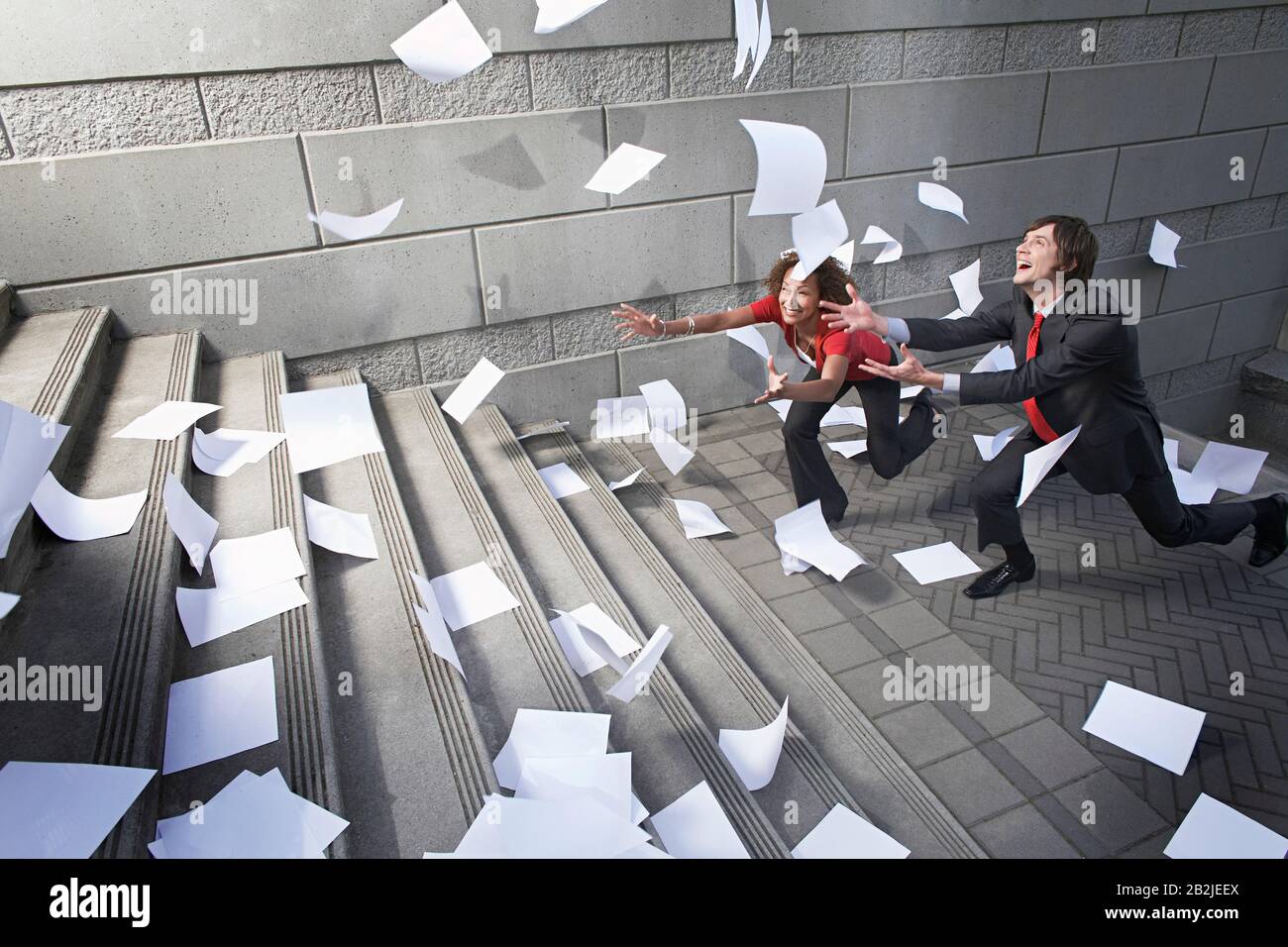 Busines man and woman catching falling paperwork on steps Stock Photo ...