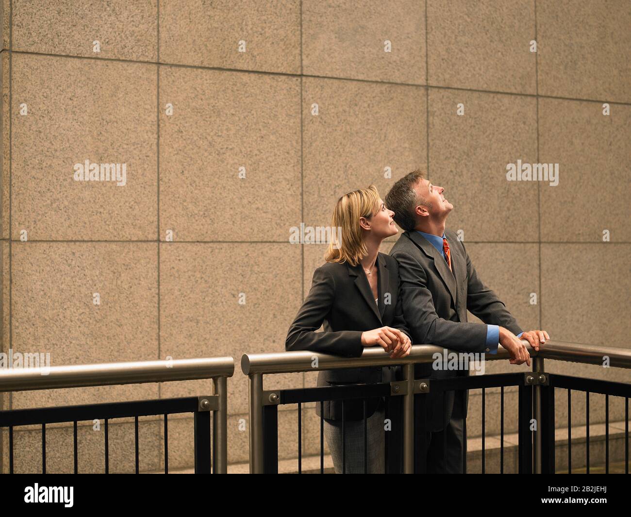 Two people leaning against railing looking up Stock Photo - Alamy