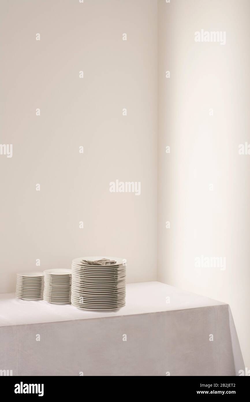 Three stacks of plates and cutlery on table Stock Photo - Alamy
