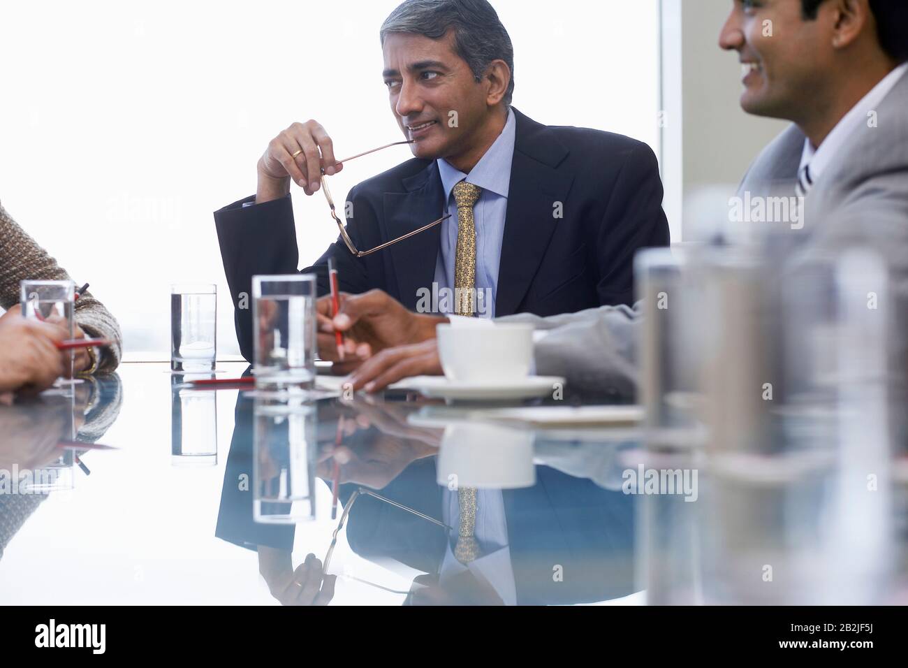 Businessman holding spectacles to mouth on business meeting close-up ...