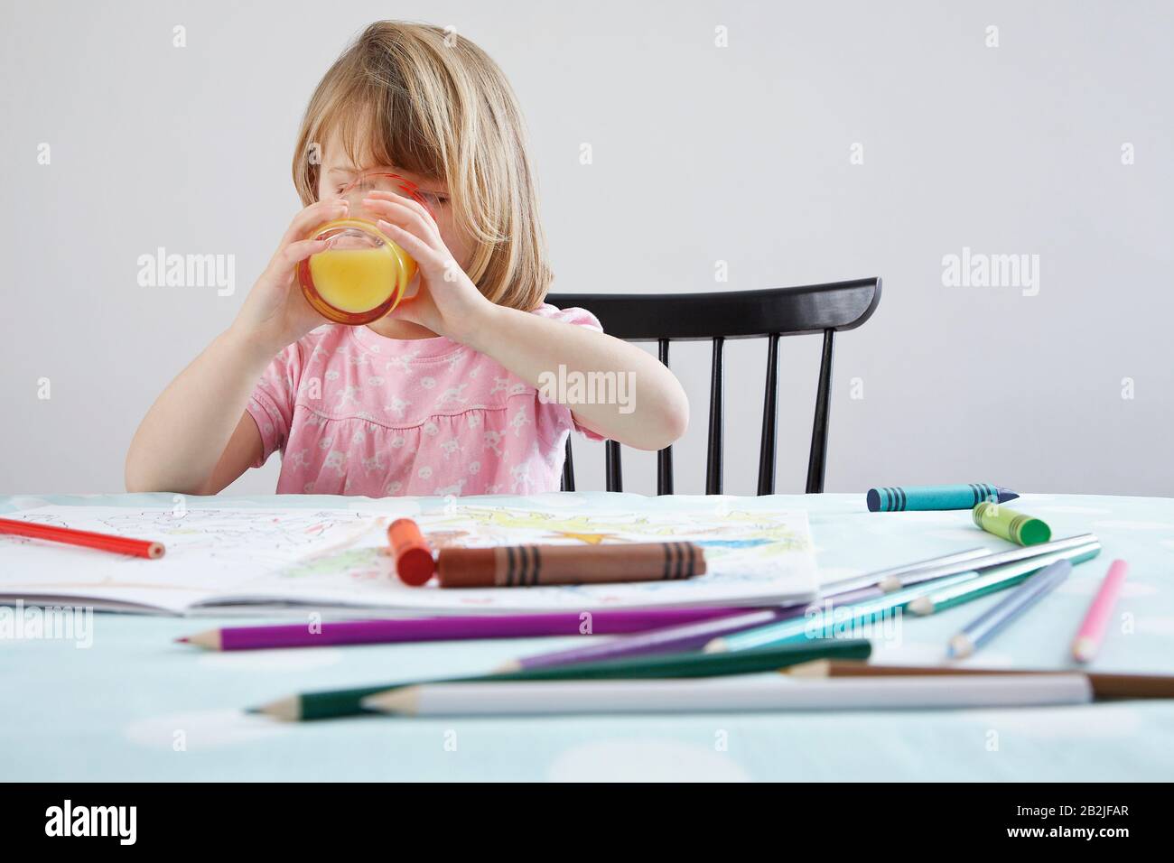 Girl (3-4) drinking orange juice crayons in foreground Stock Photo - Alamy