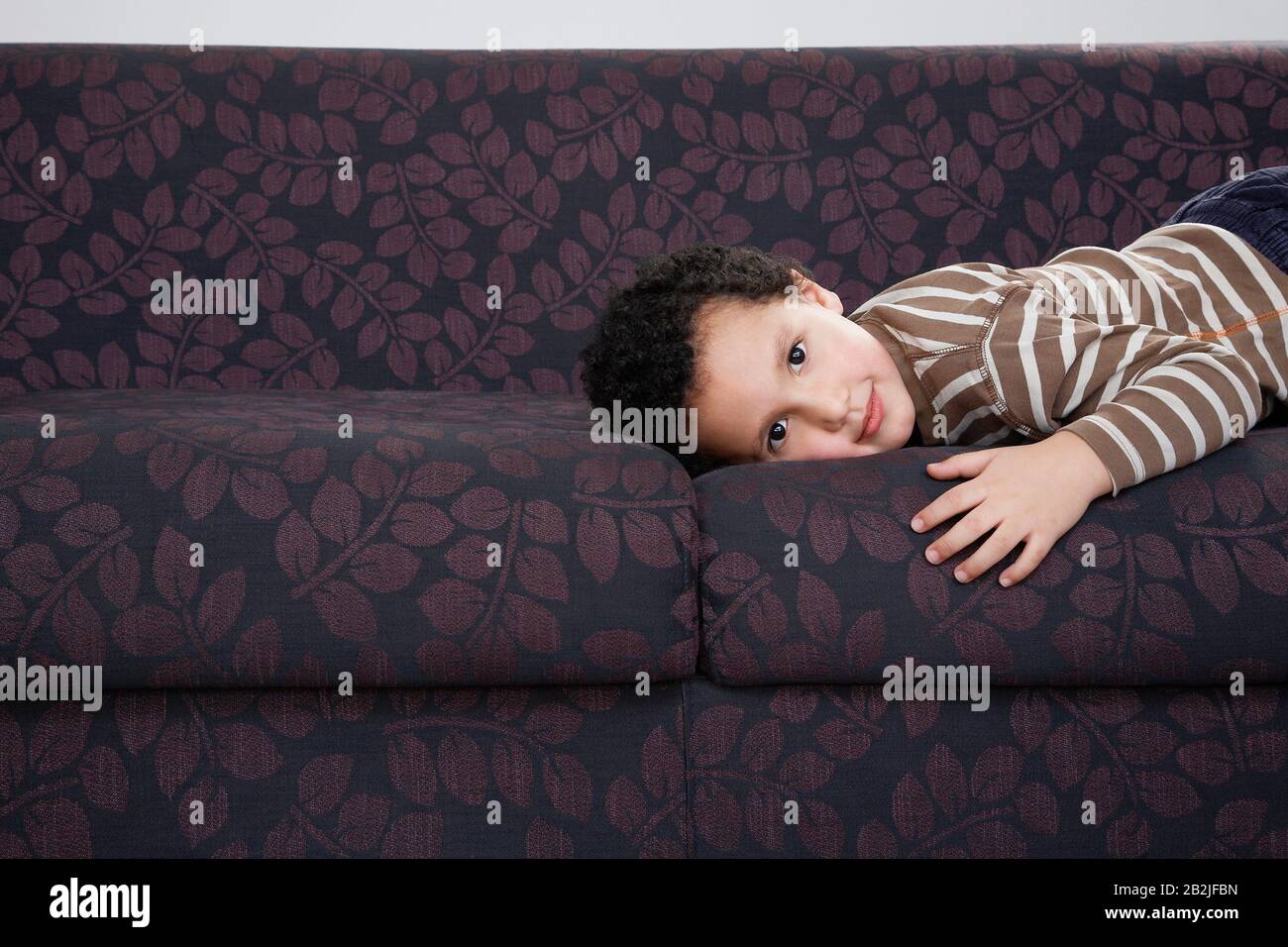 Boy (5-6) lying on sofa portrait Stock Photo - Alamy