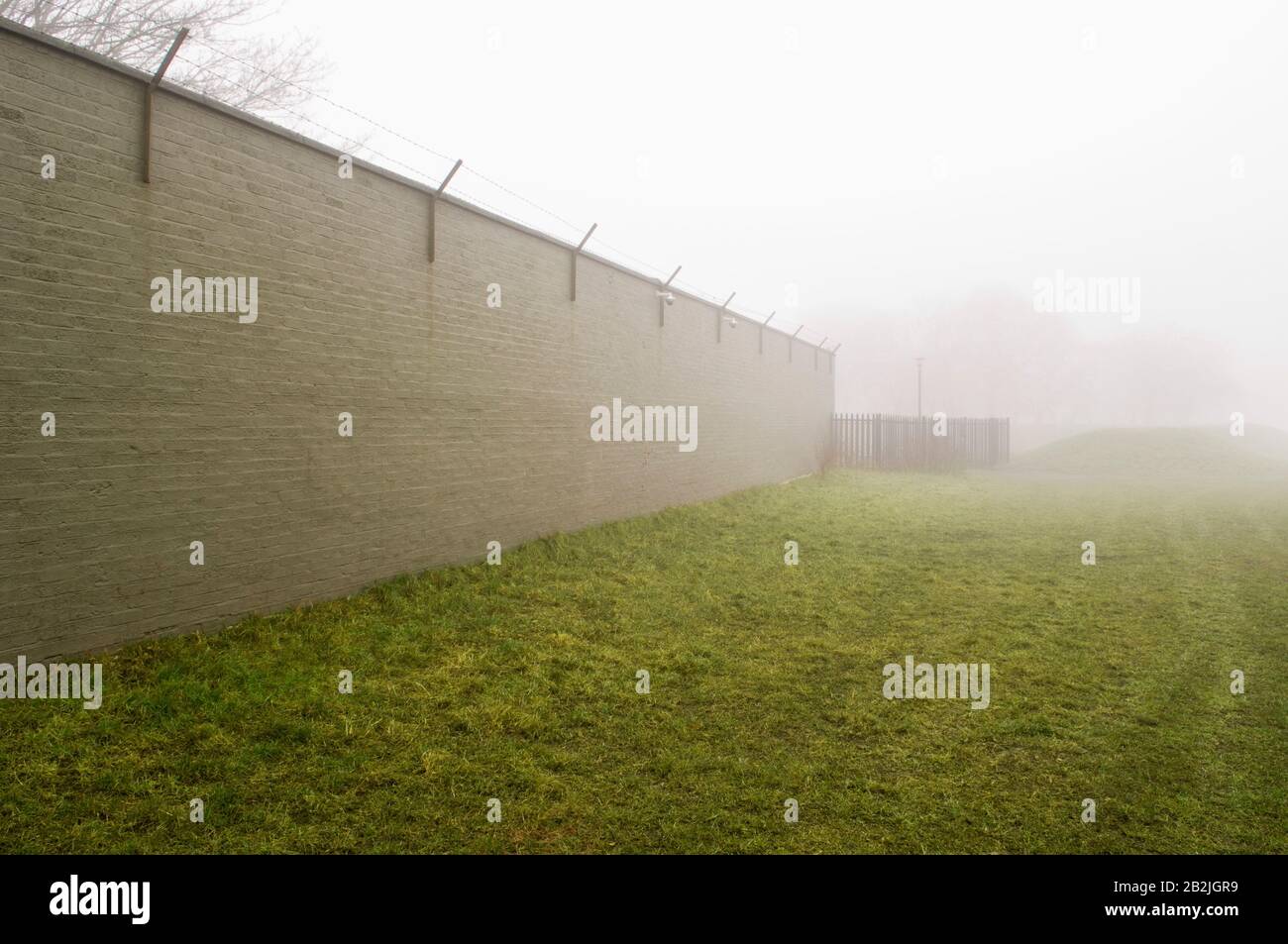 Brick wall surrounding field Stock Photo - Alamy
