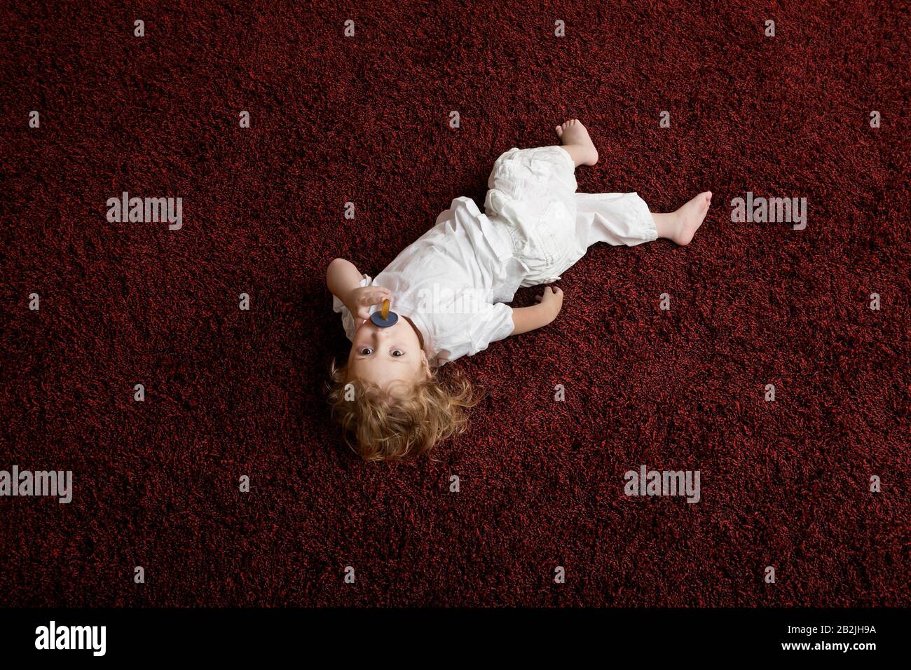 Young child lying on carpet Stock Photo - Alamy