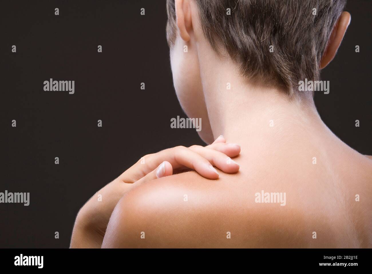 Back view of young woman touching her shoulder Stock Photo - Alamy