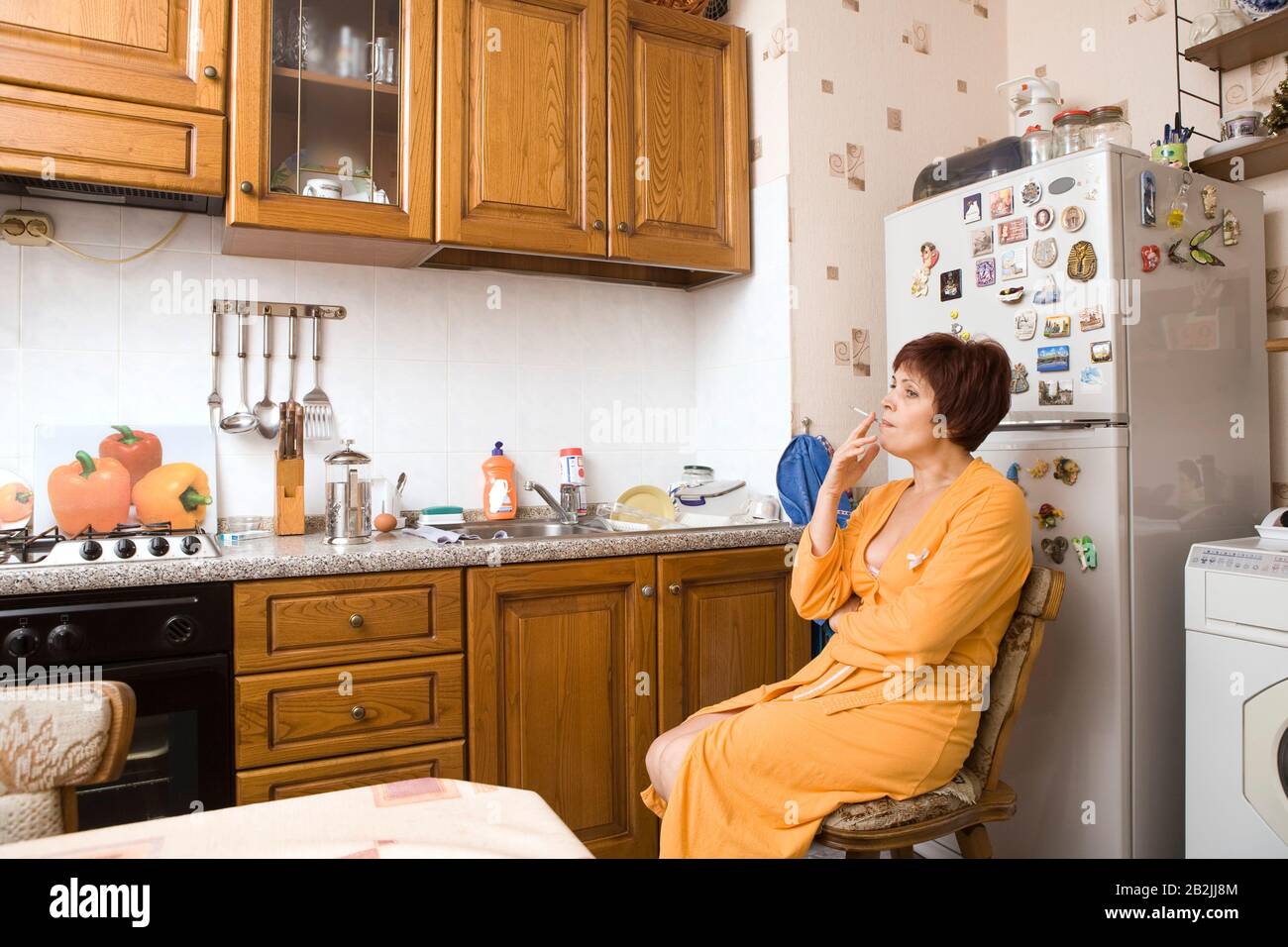 Woman smoking in kitchen Stock Photo - Alamy