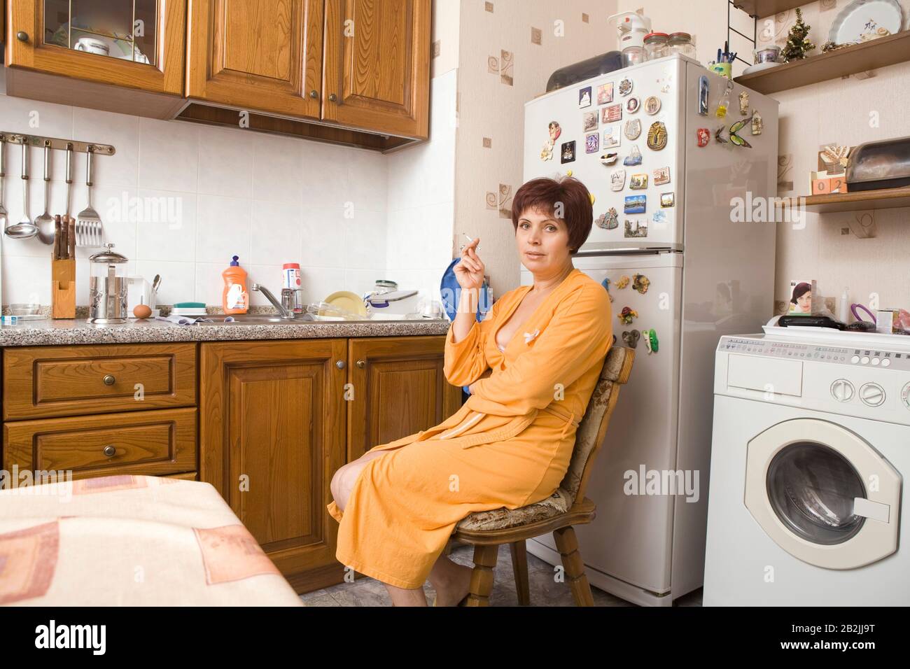 Woman smoking in kitchen Stock Photo - Alamy