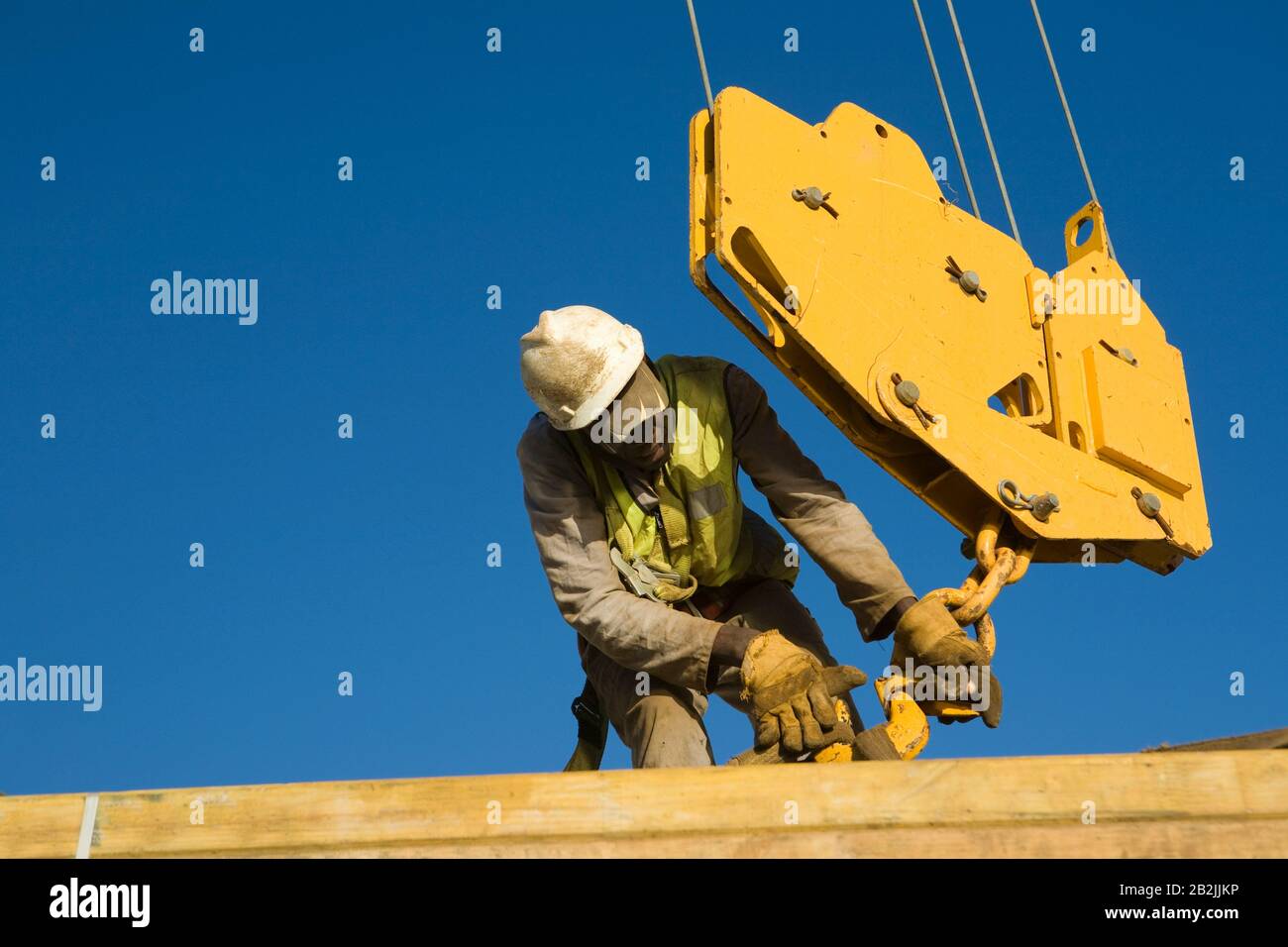 Workman secures harness for hook block Stock Photo - Alamy