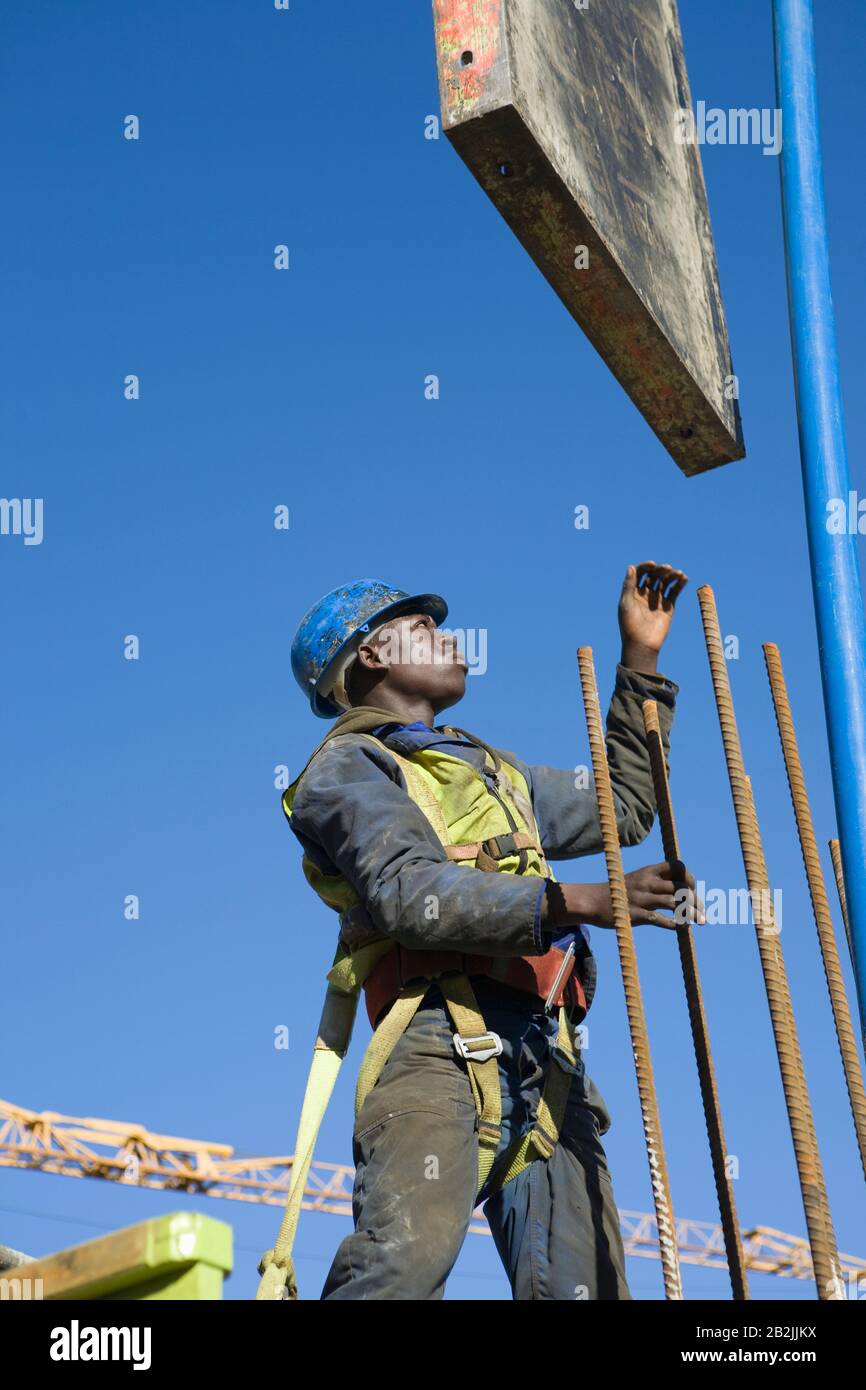 Workman lowers concrete block to steel rods on construction site Stock ...