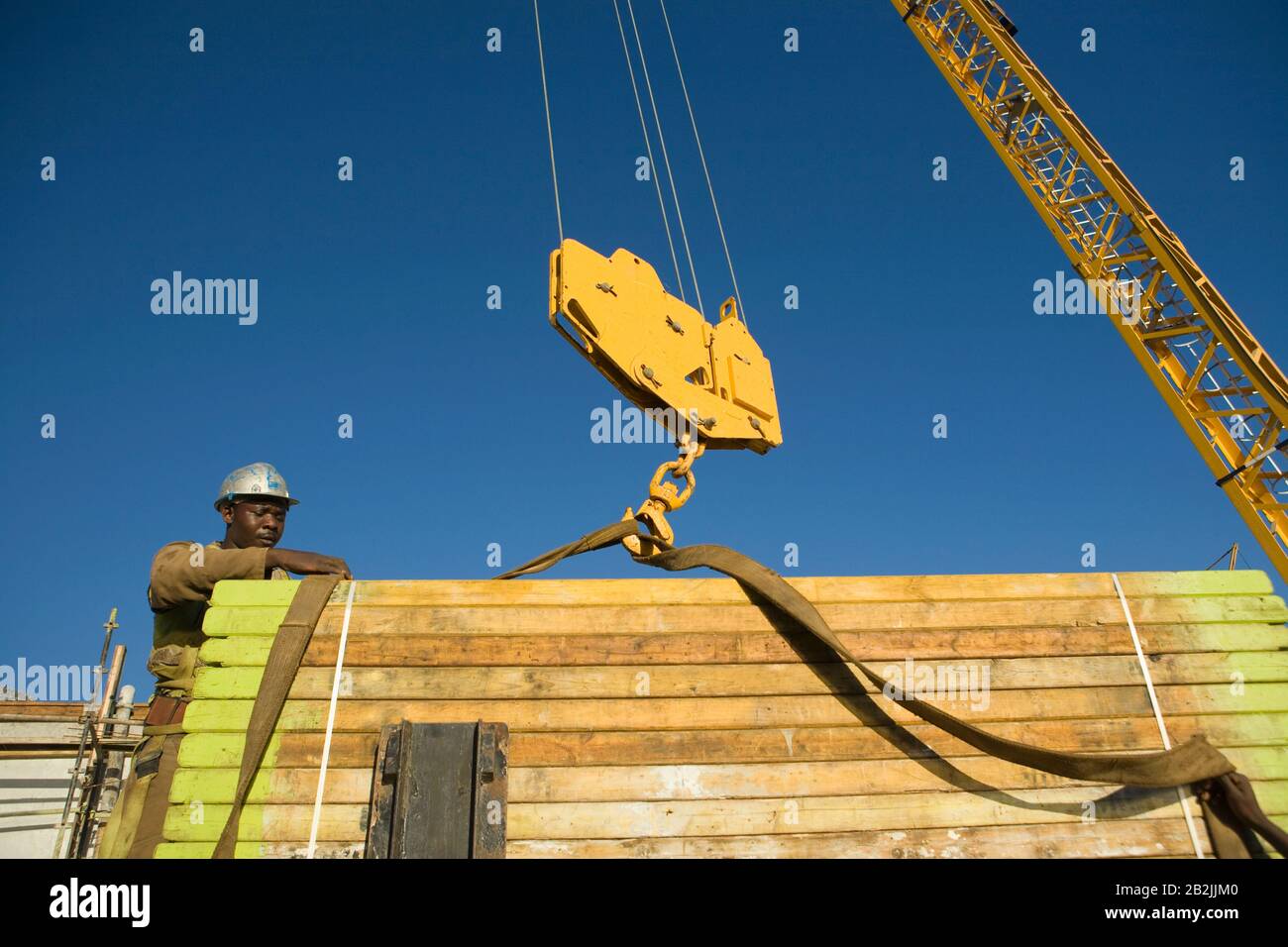 Workman secures harness for hook block on tower crane Stock Photo - Alamy