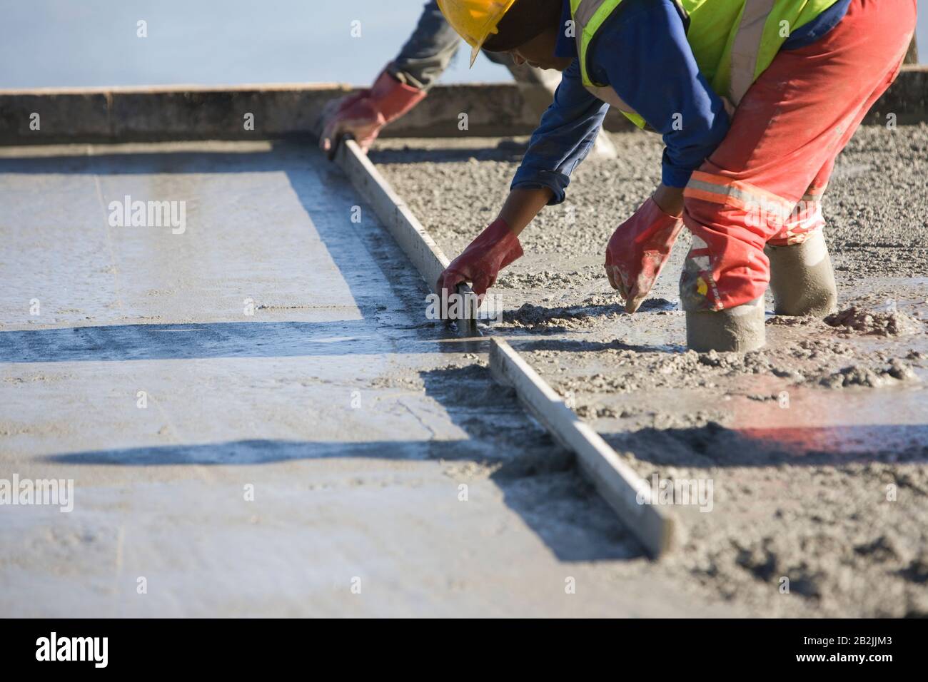 Workmen level concrete on construction site Stock Photo - Alamy