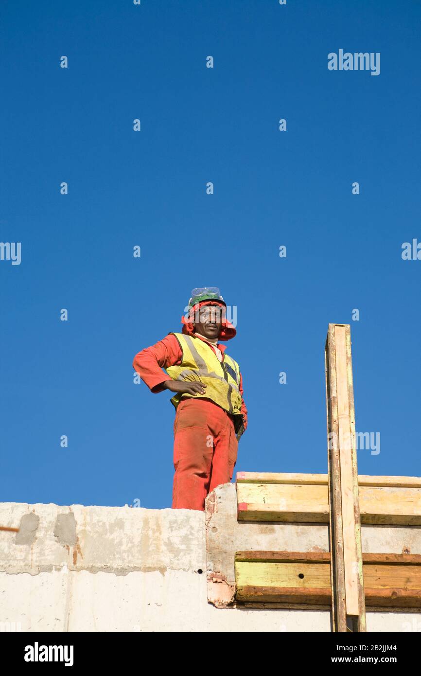Construction worker stands with hands on hips on incomplete building ...