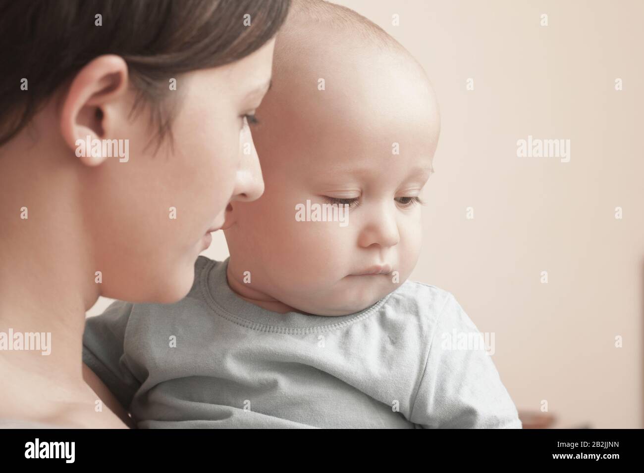 Mother holds serious toddler Stock Photo - Alamy