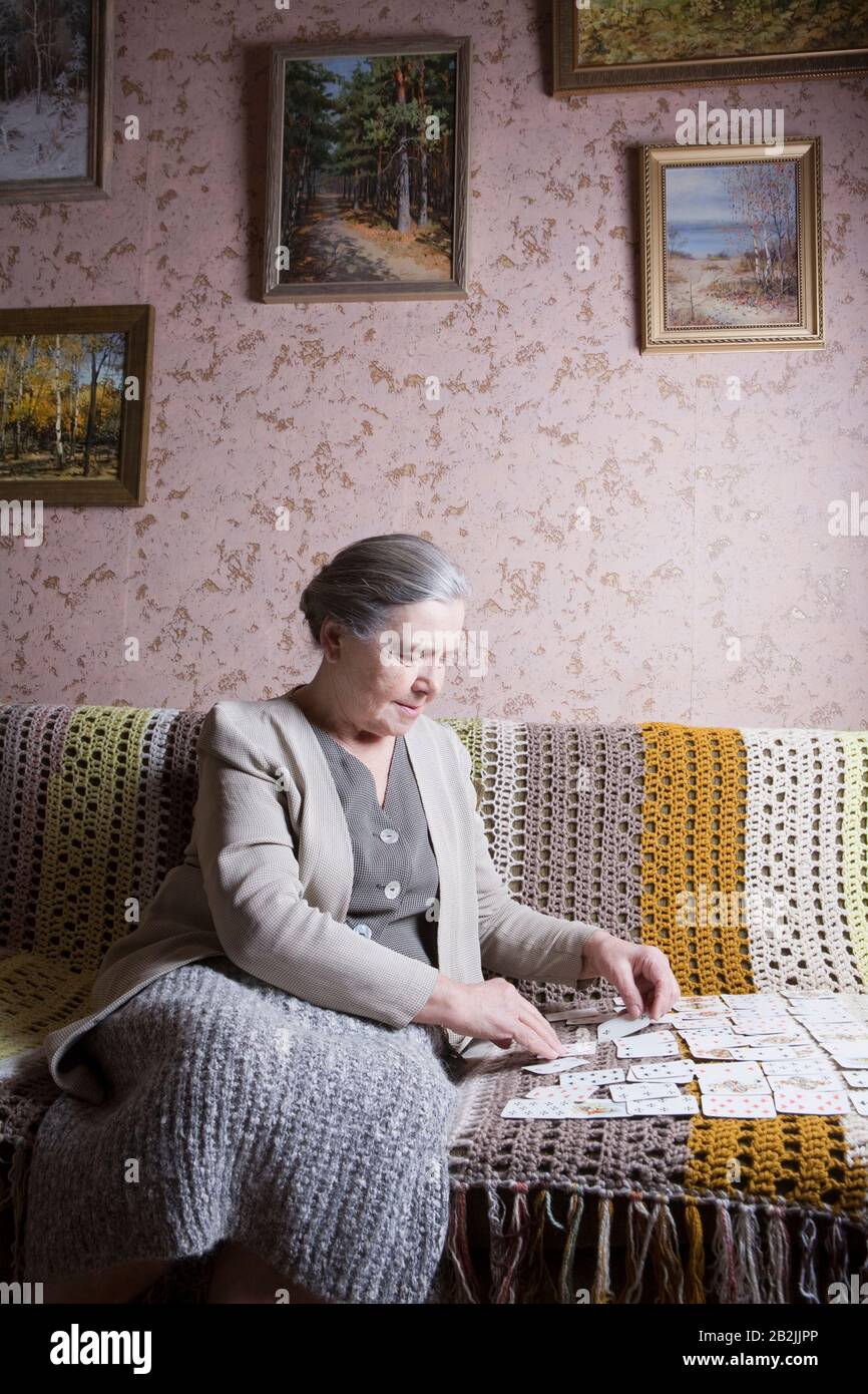 Elderly lady sits playing cards alone Stock Photo - Alamy