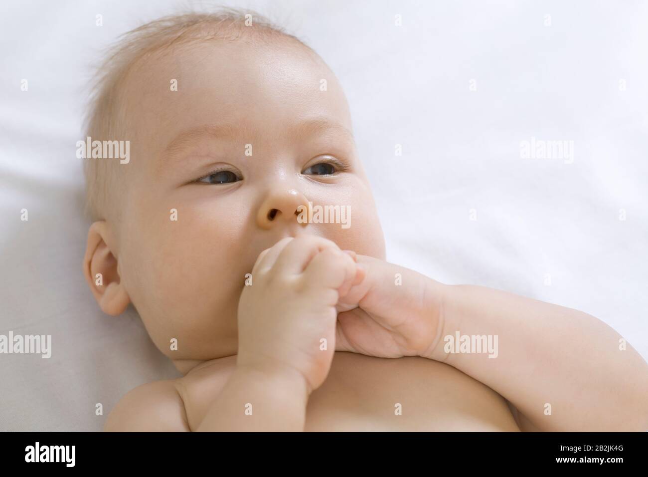 Infant child chewing fists Stock Photo - Alamy