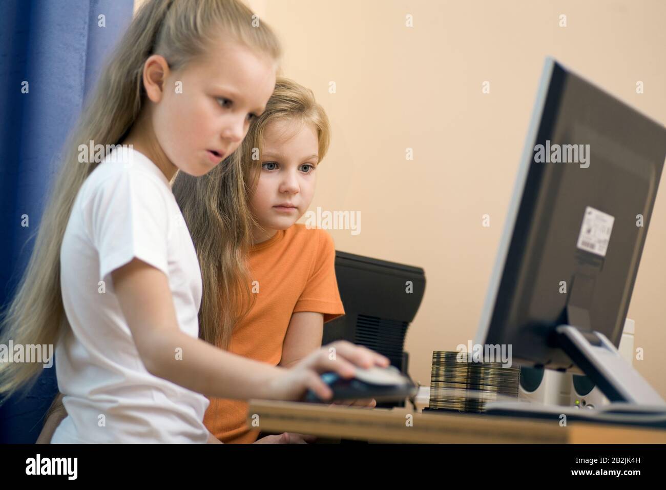 Two girls stand at computer on desk in apartment Stock Photo - Alamy