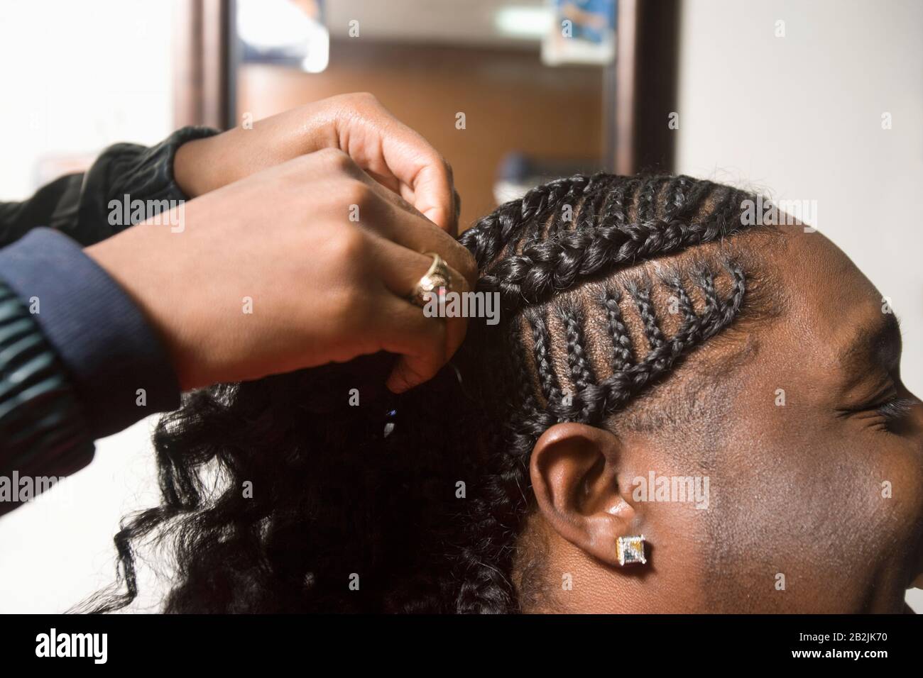 A young man having his cornrows done in the barbers Stock Photo - Alamy