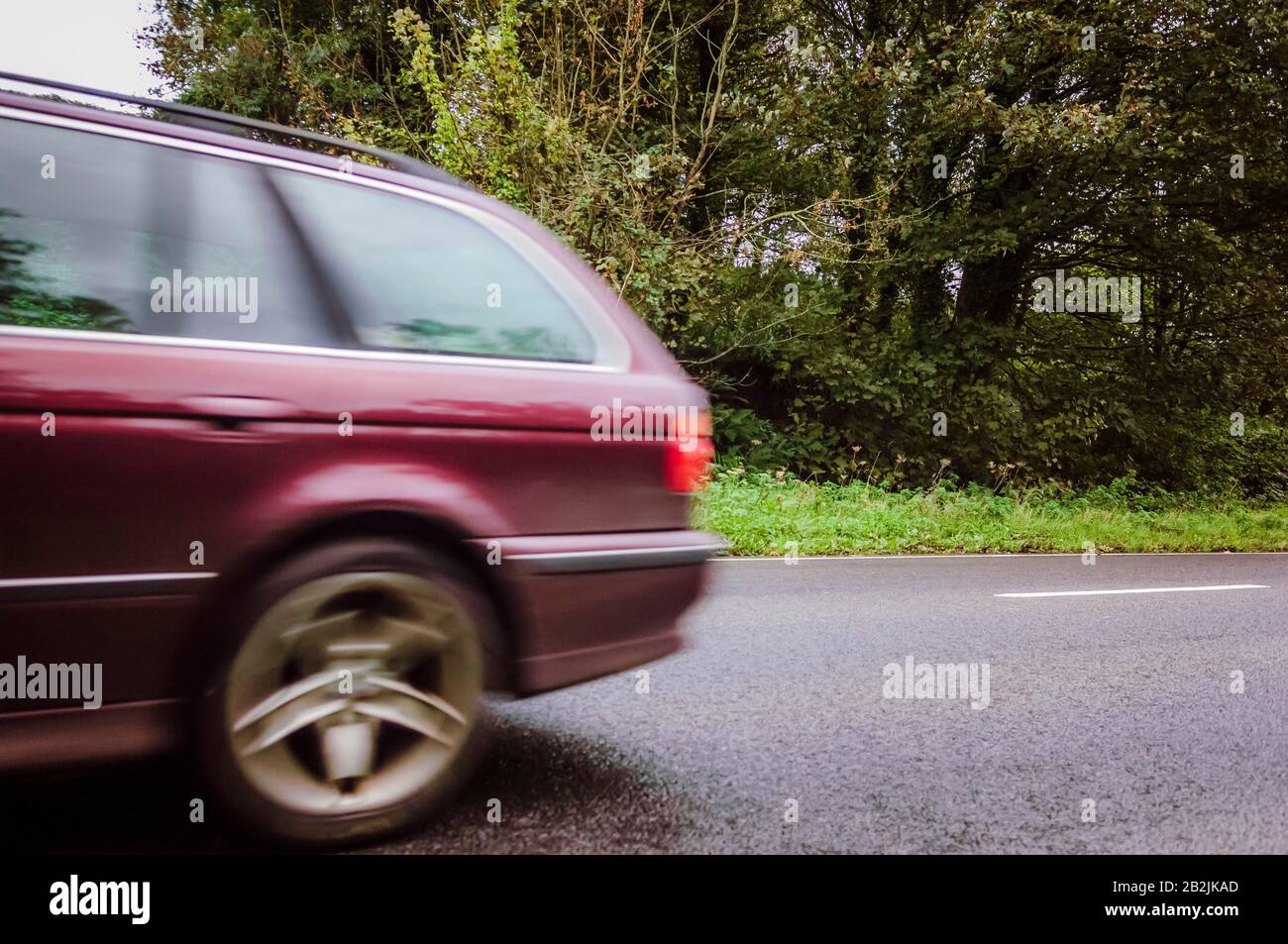 Speeding car pictured from the side driving left on a country lane ...