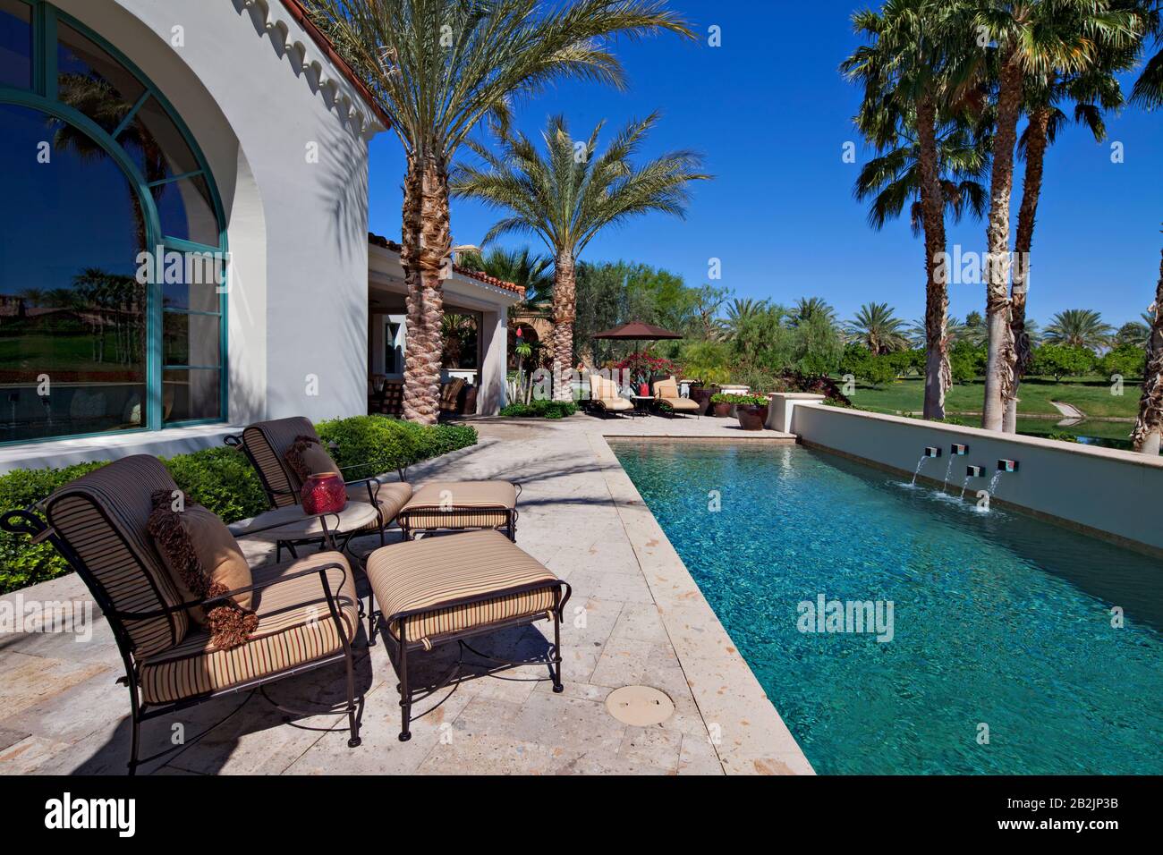 Chaise lounges at poolside in luxury villa Stock Photo - Alamy