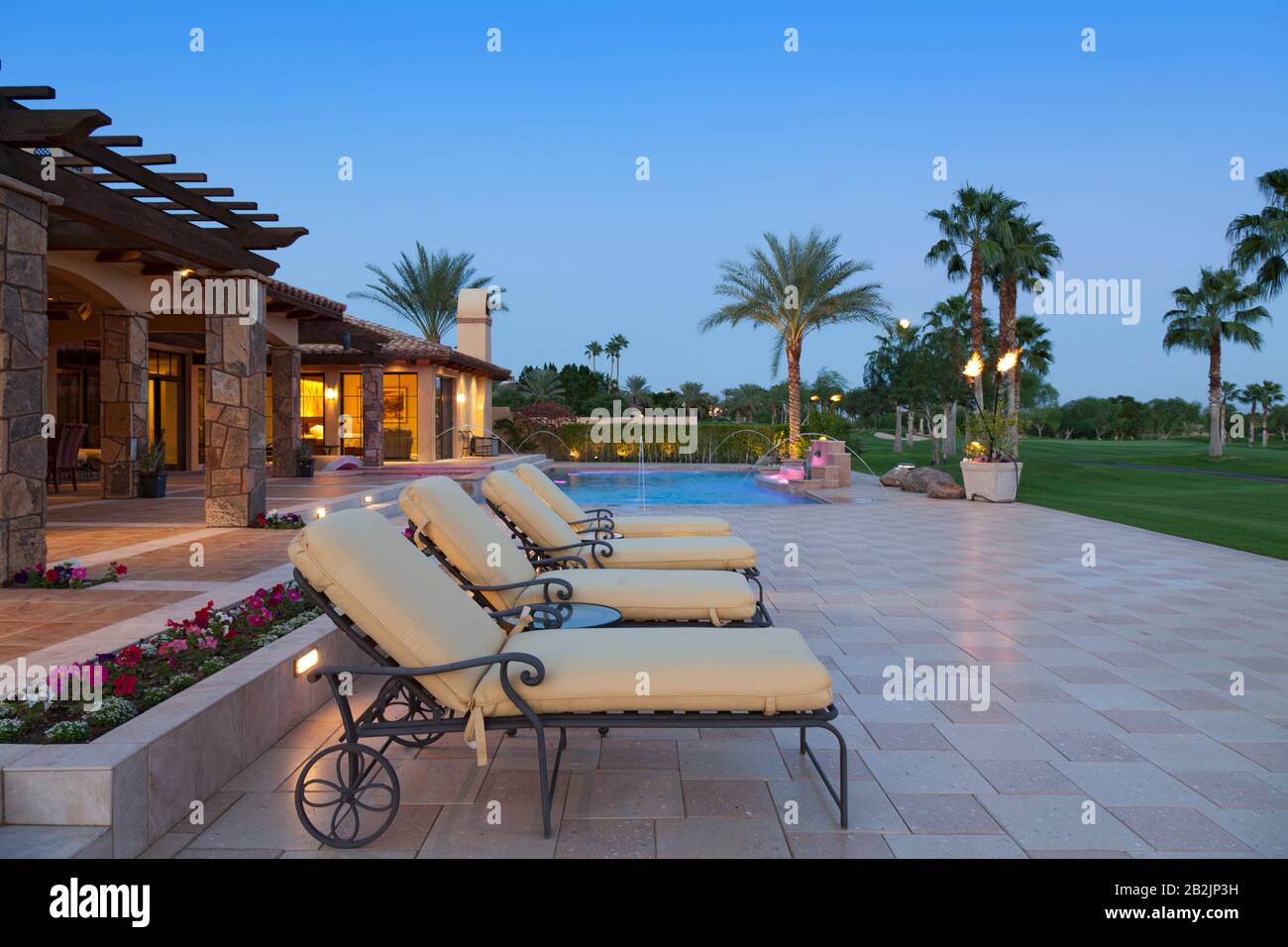 Sun loungers in patio at poolside outside luxurious manor house Stock ...