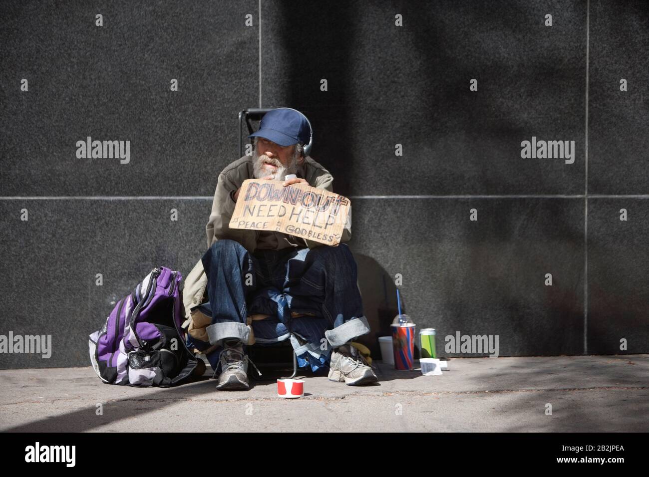 Homeless person sitting with a placard on sidewalk Stock Photo - Alamy