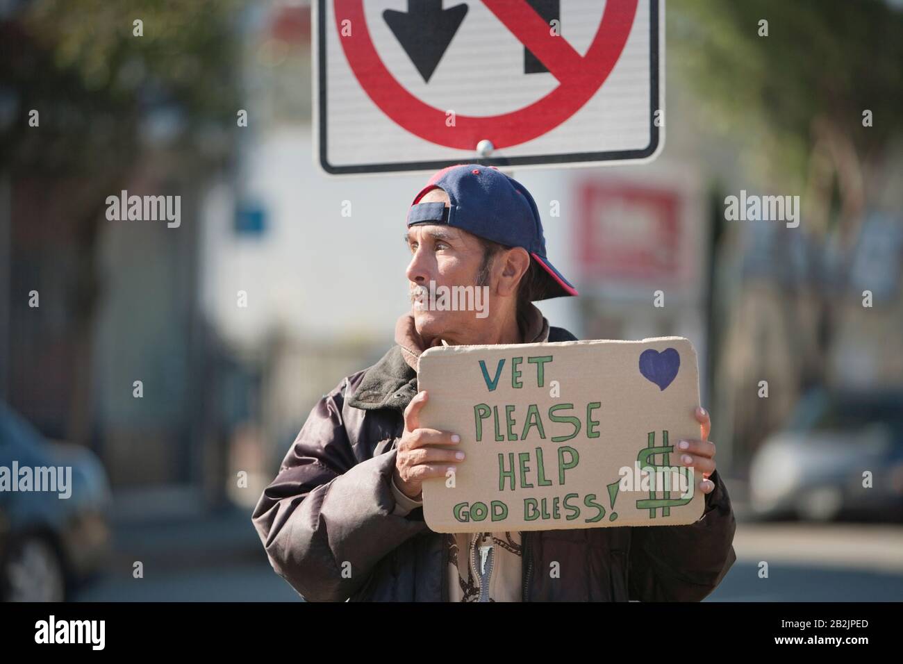 Homeless person with placard in front of road sign Stock Photo - Alamy