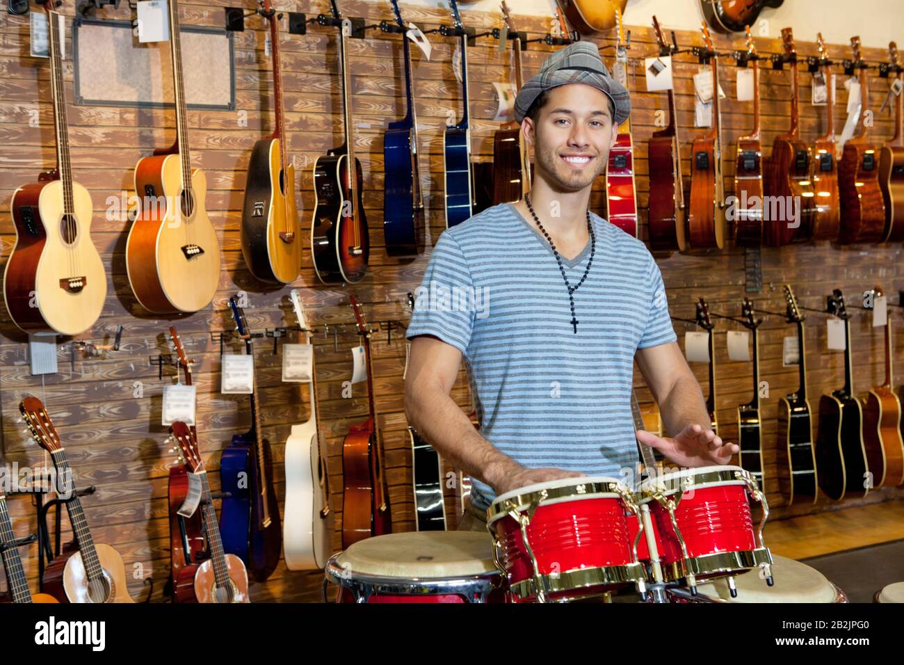 Portrait of a happy man playing bongo drums in music store Stock Photo ...