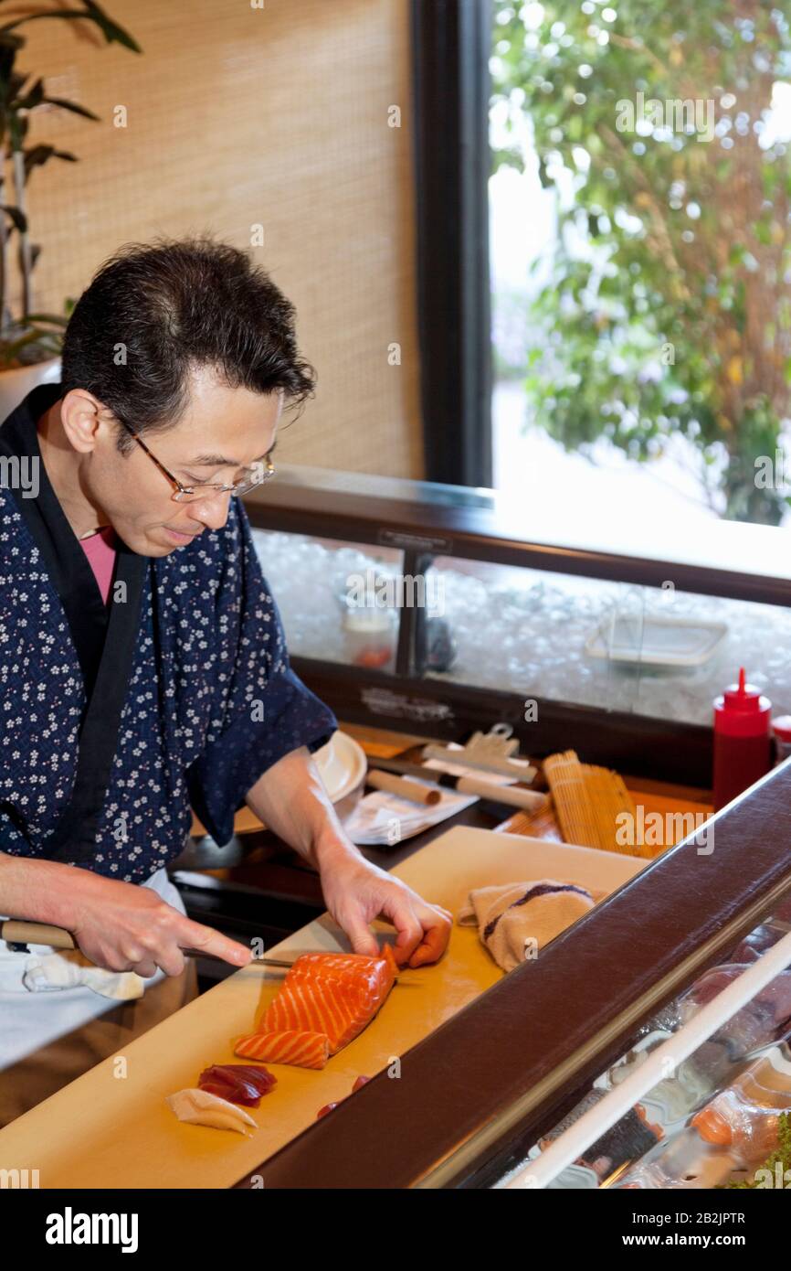 Mature Asian chef cutting fish in restaurant Stock Photo - Alamy