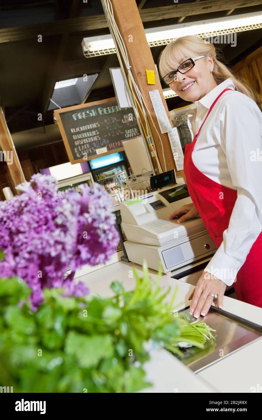 Portrait of a senior employee at checkout counter in market Stock Photo ...