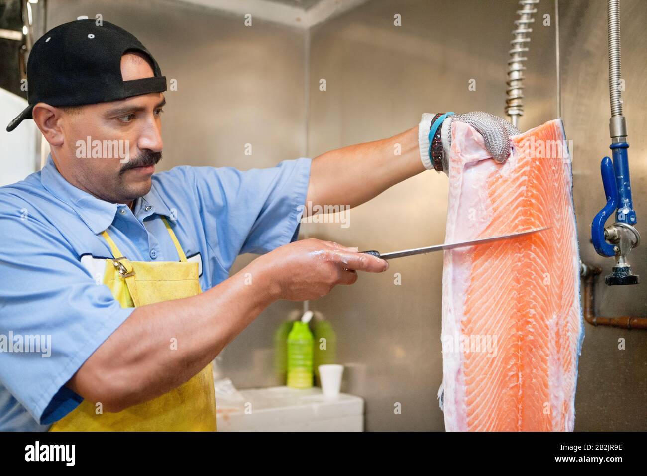Mature fishmonger slicing salmon fish Stock Photo - Alamy