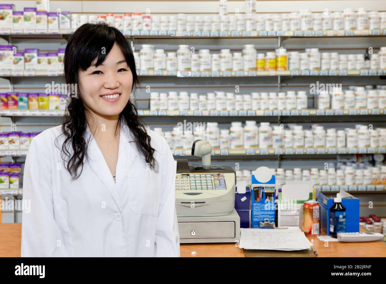 Portrait of a happy Asian woman employee standing with counter in ...