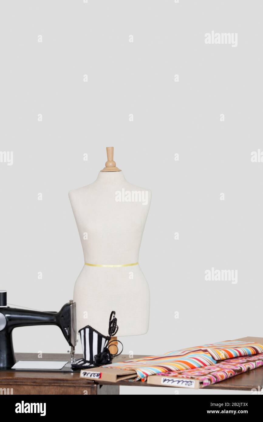 Tailor's dummy with hat and cloth pattern on sewing machine over ...