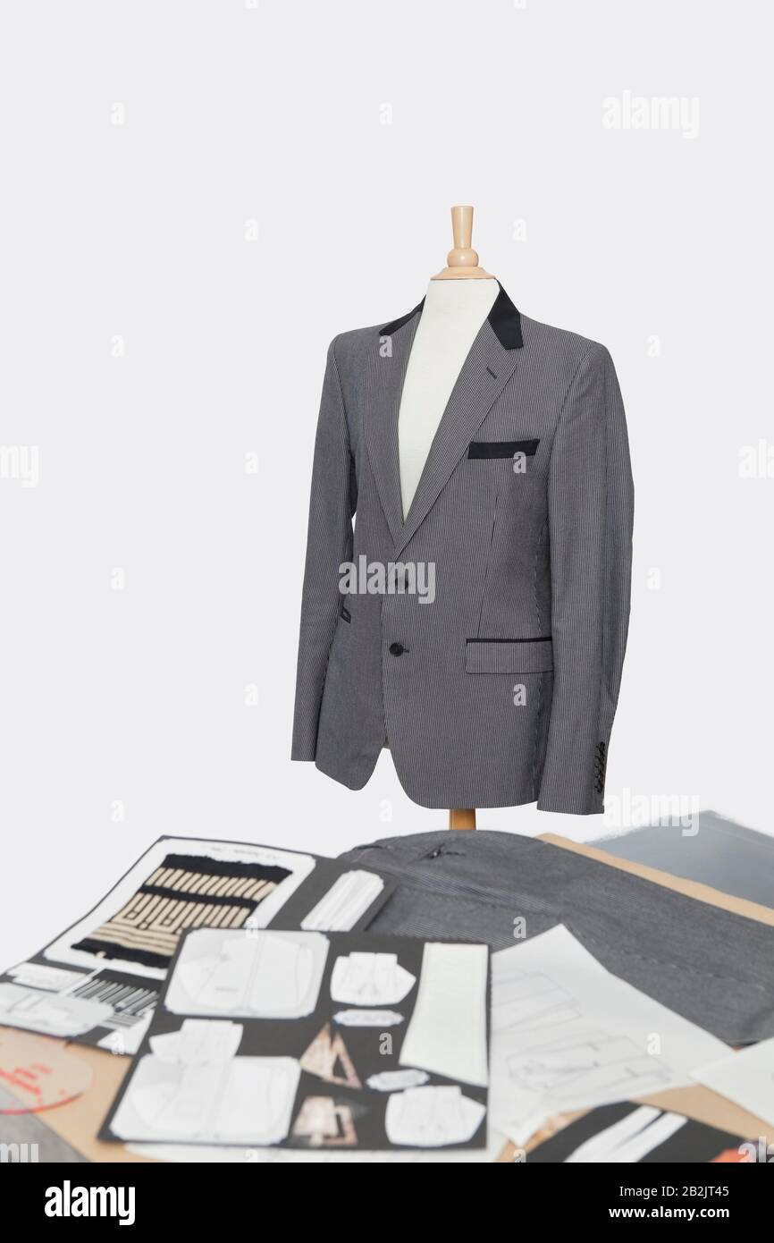 Suit on tailor's dummy with design layouts over gray background Stock ...