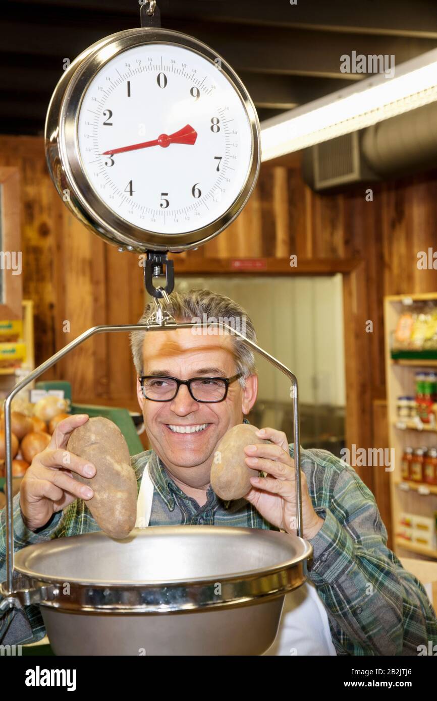 Happy mature man measuring potato in weight scale Stock Photo - Alamy