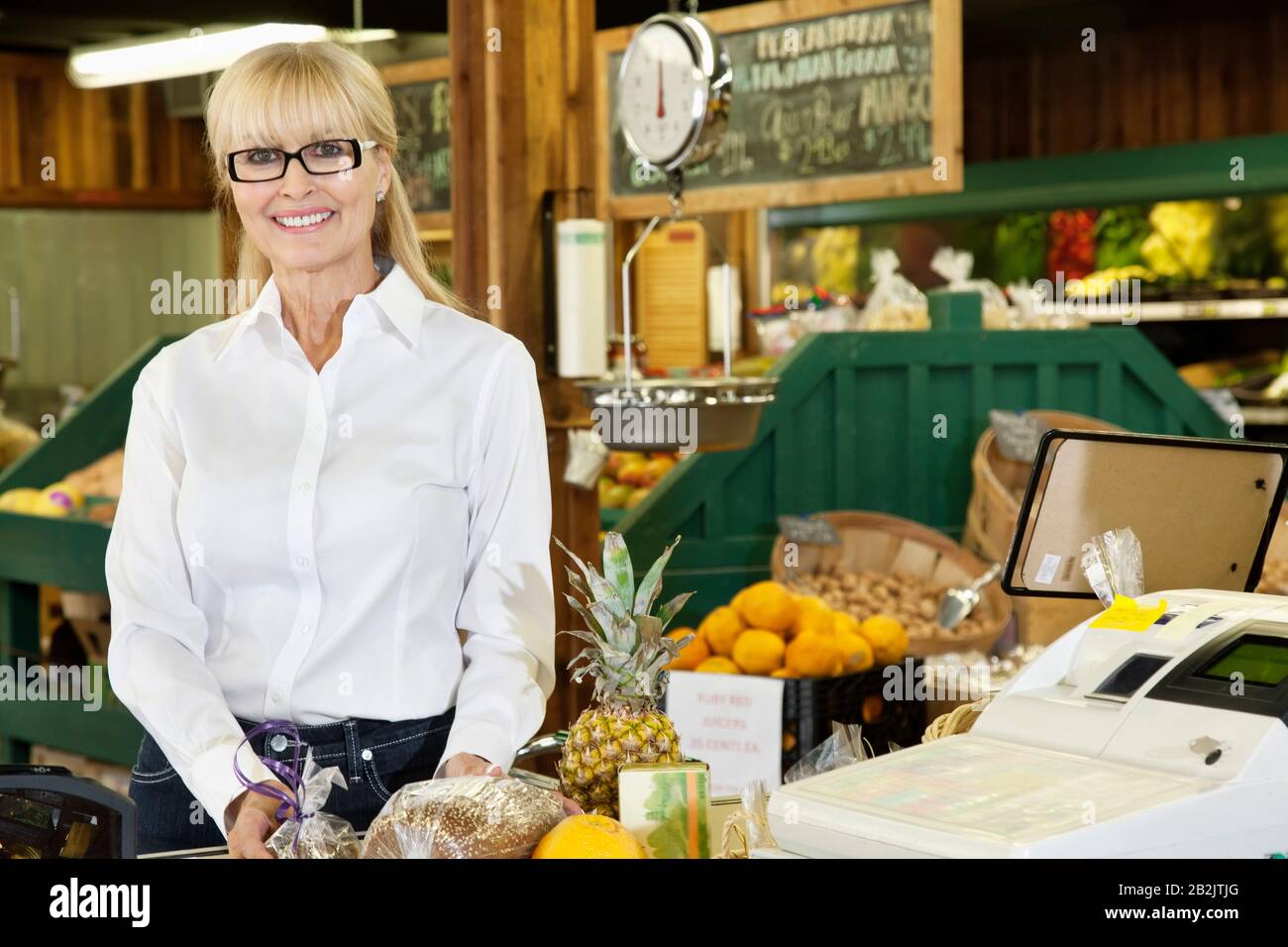 Portrait of a happy senior woman standing by checkout counter Stock ...