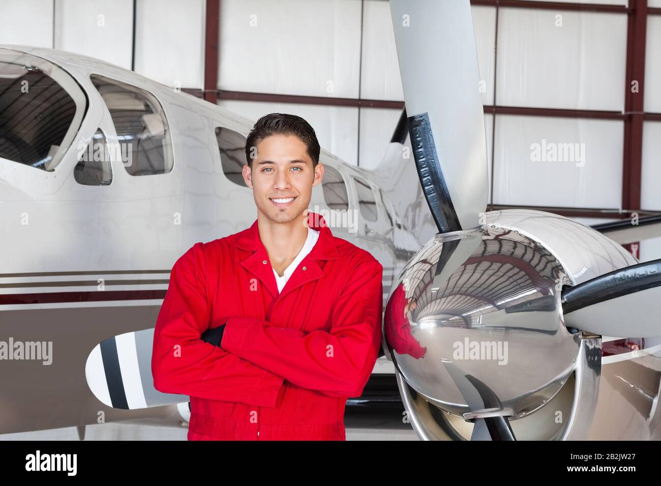 Portrait of young aeronautic engineer standing in front of airplane ...