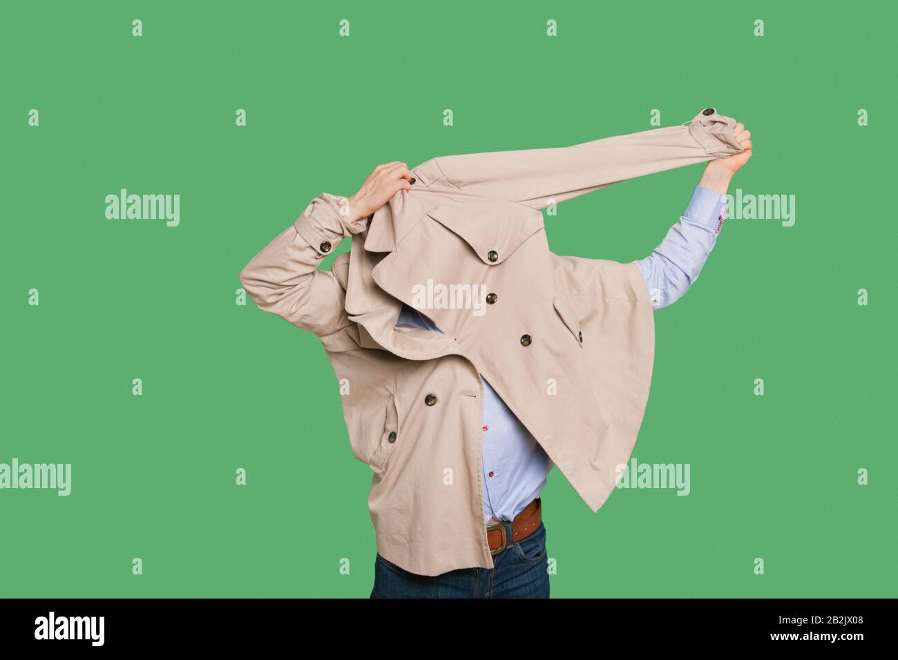 Man struggling to wear jacket over colored background Stock Photo - Alamy