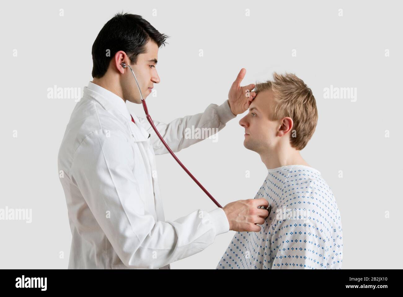 Side view of doctor examining male patient with stethoscope Stock Photo ...