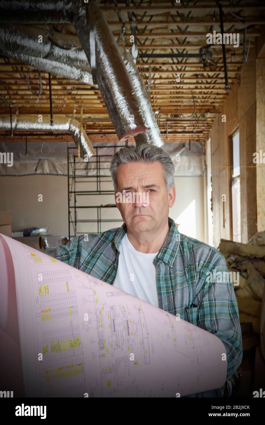 Portrait of mature architect with blueprint at construction site Stock ...