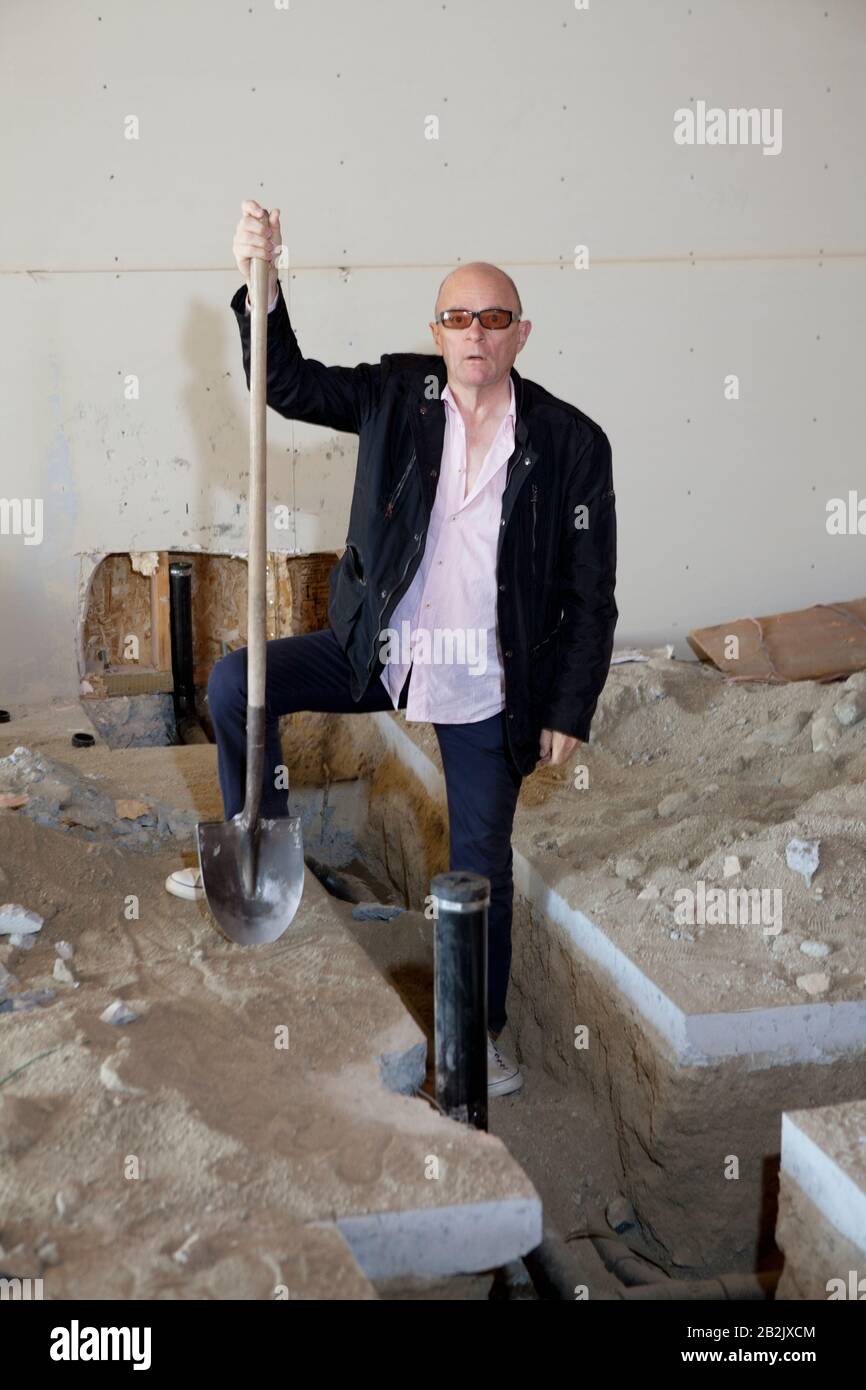 Portrait of senior owner of property standing with shovel at ...