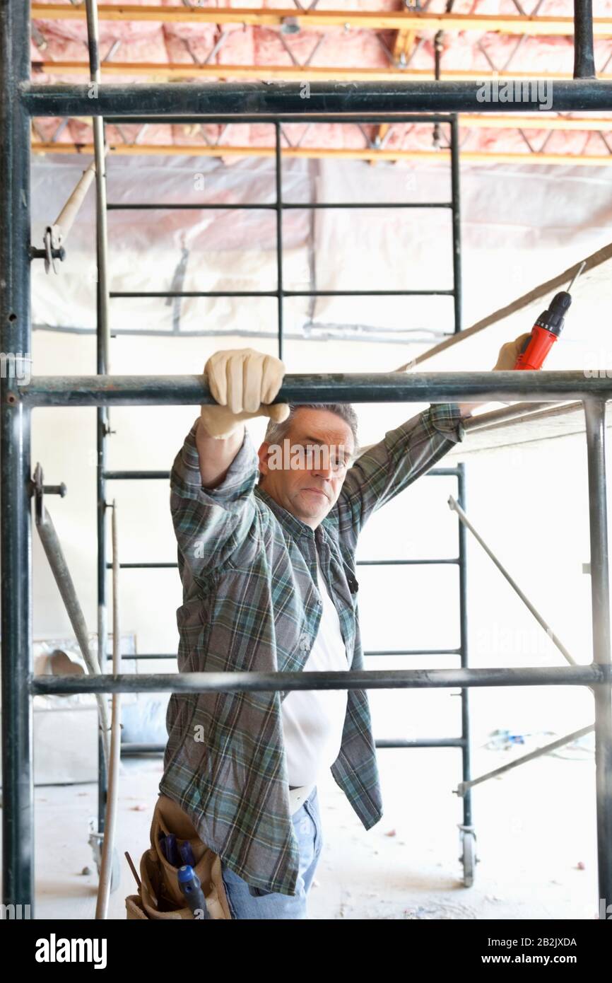 Portrait of contractor with drill standing under scaffolding Stock ...