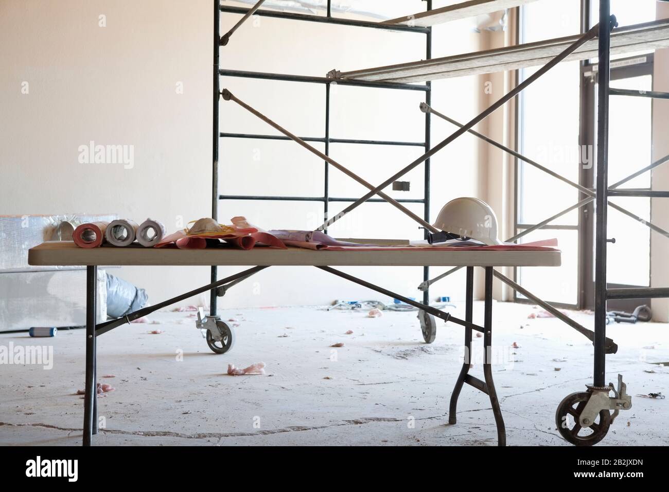 Table with blueprints and hardhat in front of scaffold in construction ...