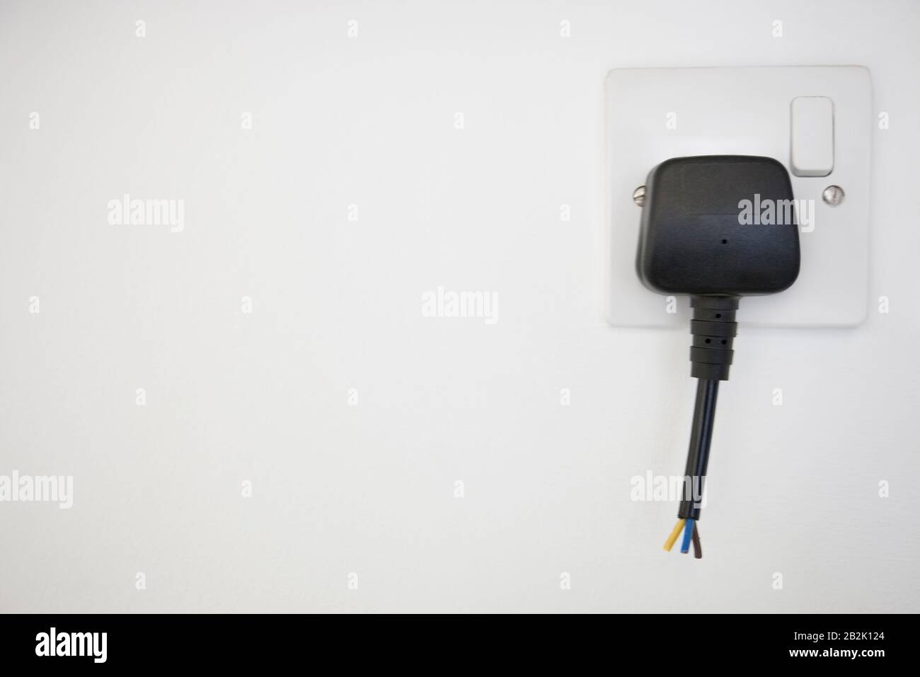Frayed electrical cord with outlet attached on white wall Stock Photo ...