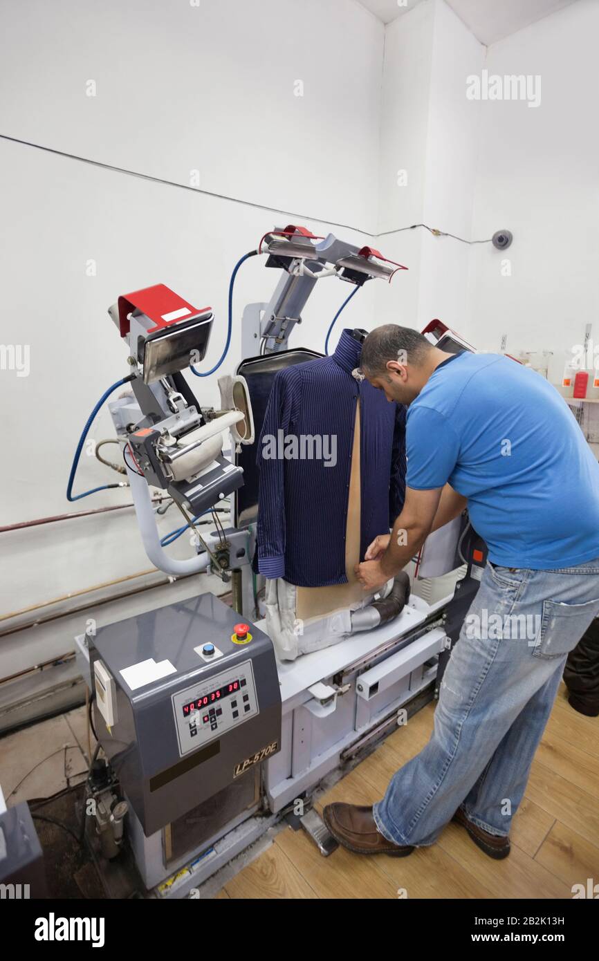 Man adjusting shirt on laundry dummy machine at launderette Stock Photo ...