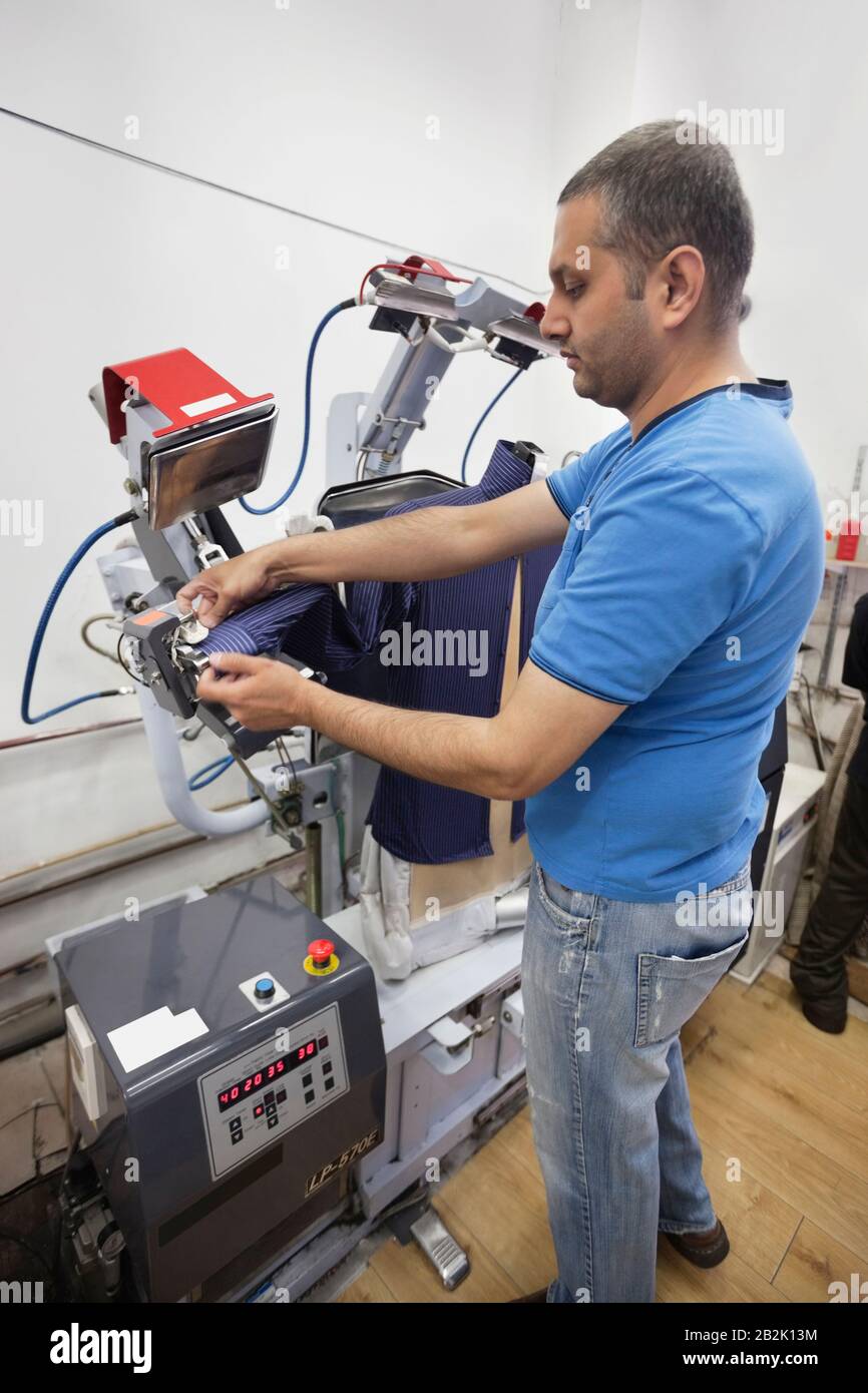 Man adjusting shirt on laundry dummy machine at launderette Stock Photo ...