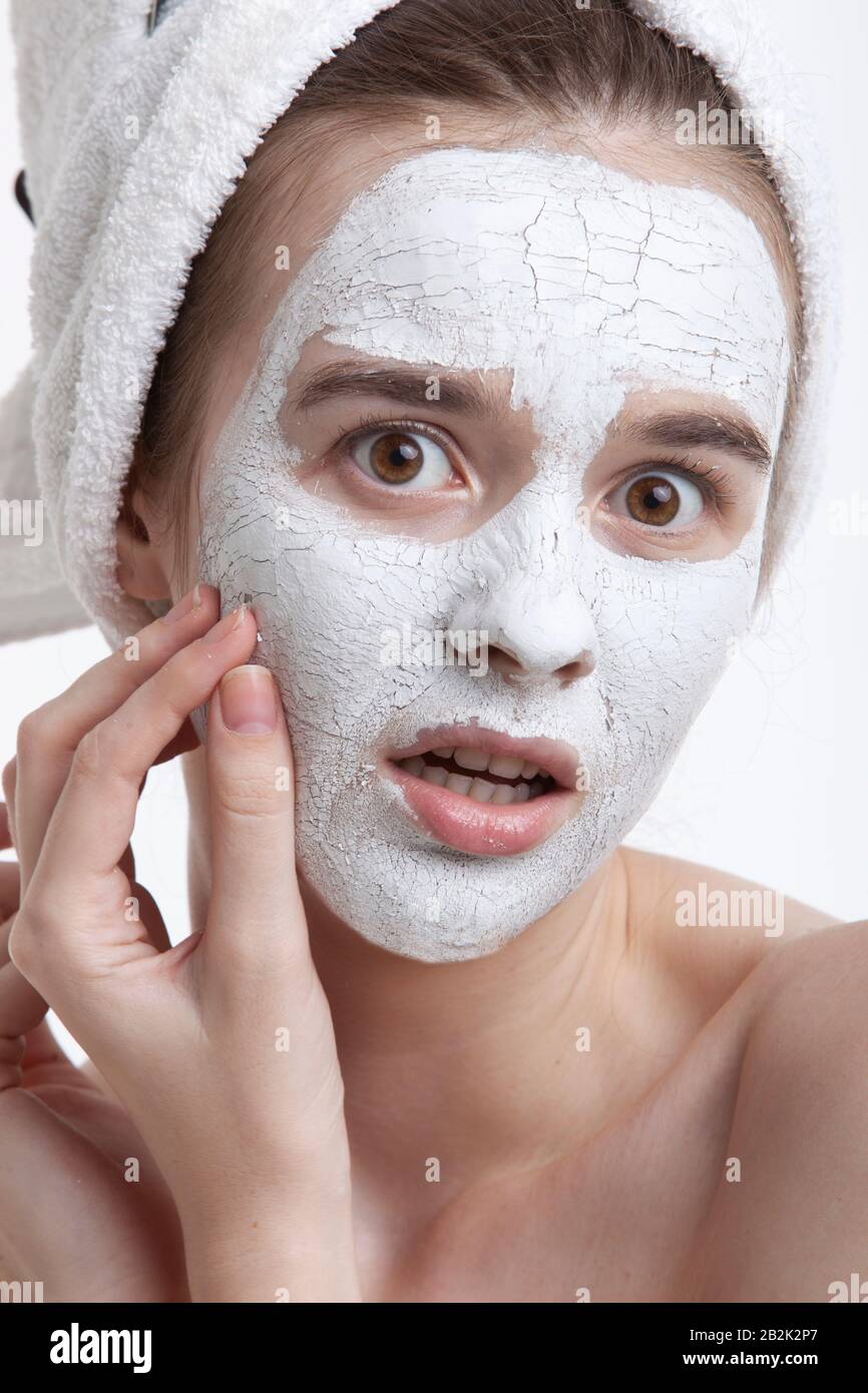 Portrait of shocked young woman with face mask peeling off against ...