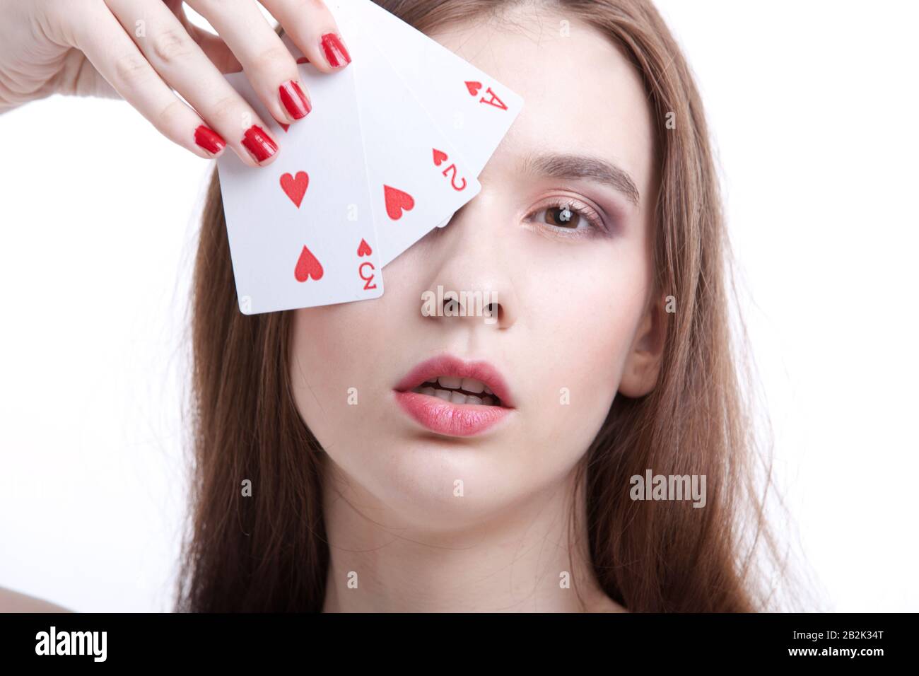 Portrait of beautiful young woman covering her eyes with playing cards ...