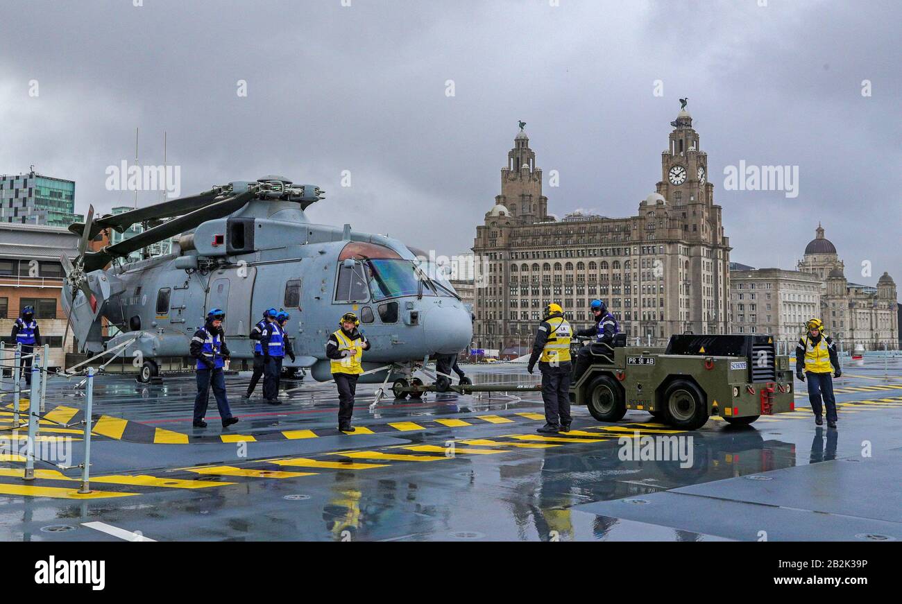 A Merlin helicopter is lifted onto the deck of the Royal Navy aircraft ...