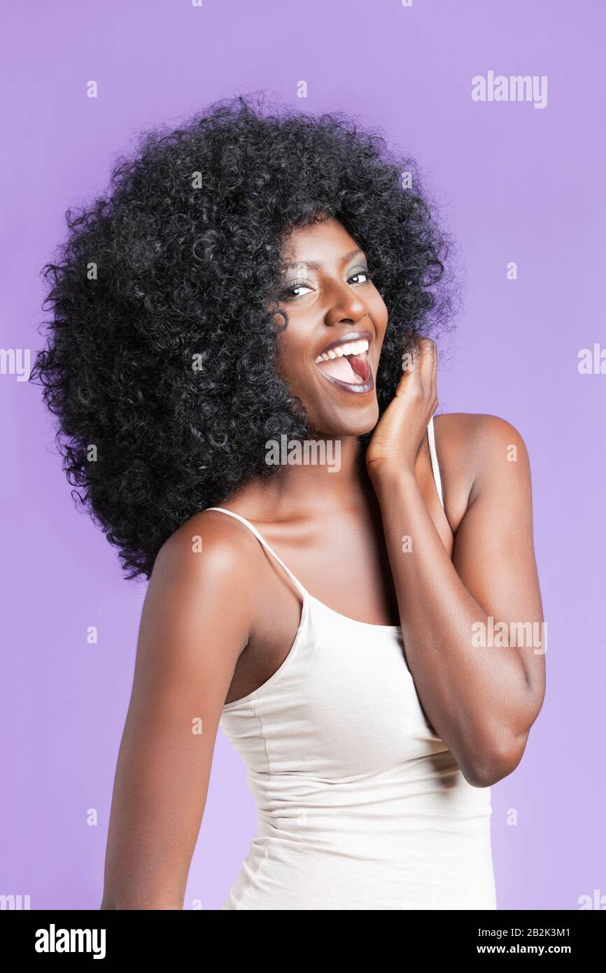 Portrait of young woman with fizzy hairstyle standing over violet background Stock Photo - Alamy